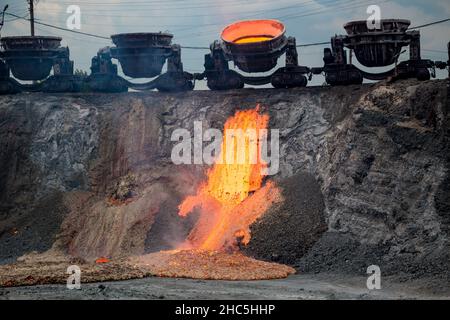 Colorful stream of molten metal at a steel mill. Blast furnace slag at ...
