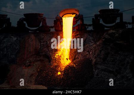 Colorful stream of molten metal at a steel mill. Blast furnace slag at ...
