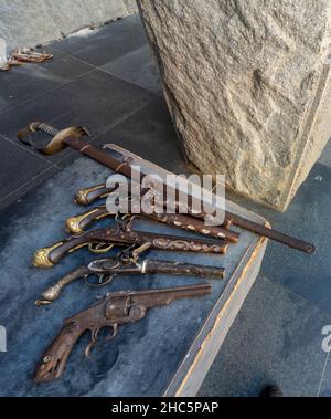 Rusty old weapons including a revolver,powder pistols and sword laid ...