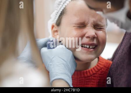 Baby girl crying in ear piercing ceremony Stock Photo - Alamy