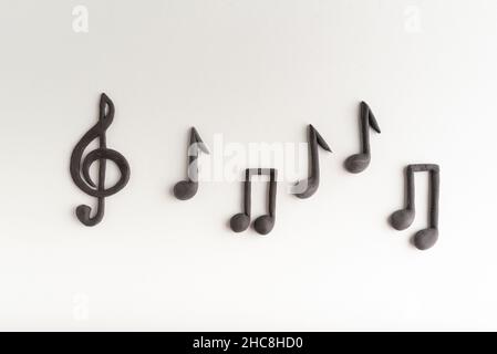Black volumetric notes and violin key on white background top view ...