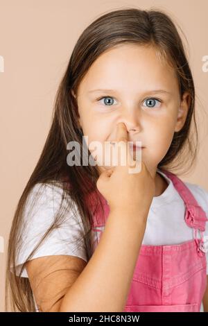 Child nose picking close up face with finger. One thoughtful little boy ...