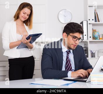 Manager giving instruction to female assistant at working place in ...