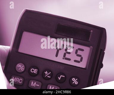 Calculator with YES on display on blue blured background. Positive ...