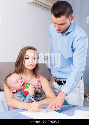 Sad woman with crying boy signing documents about share of property ...