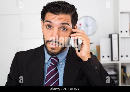 Surprised spanish businessman is talking phone with his partner in ...