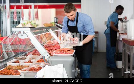 Successful owner of butcher store preparing fresh meat products for ...
