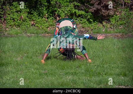 A fit nimble woman in her 50s at a meditative Yoga class in a park in ...