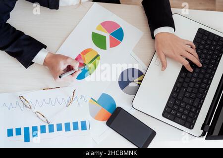 Businesswoman working with laptop keyboard and graph paper work ...