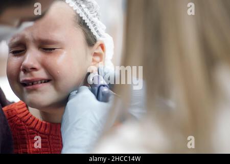 Baby girl crying in ear piercing ceremony Stock Photo - Alamy