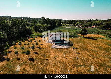 Aerial view of a stage in the middle of a field under a clear blue sky ...