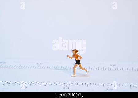 Miniature joggers while running next to a tape measure - white ...