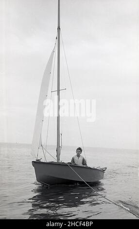 1960s, historical, a boy sailing a dinghy boat along the Norfolk Broads ...