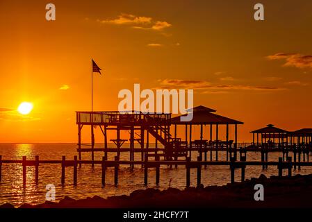 The sun sets behind boat docks and fishing piers on Coden Beach, Dec ...
