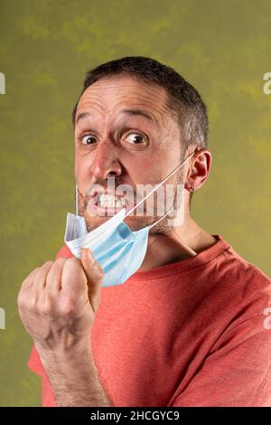 A man pulling his surgical blue mask down with anger Stock Photo - Alamy
