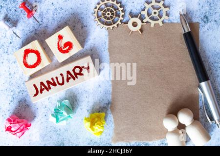 Wooden calendar 06 January with frame for photo on white table and ...