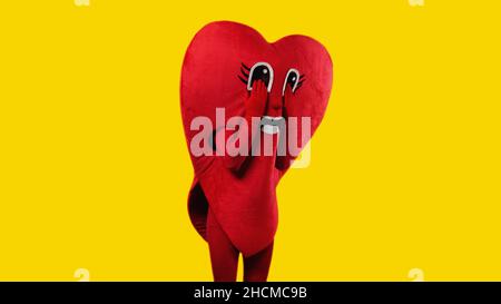 person in heart costume touching cartoon eyes isolated on yellow Stock ...