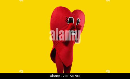 person in heart costume touching cartoon eyes isolated on yellow Stock ...