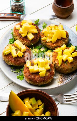 Vegan food, quinoa cutlet garnished with mango. Baked vegetarian burger ...