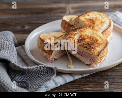 grilled ham and cheese sandwich served in a white plate and placed on a ...
