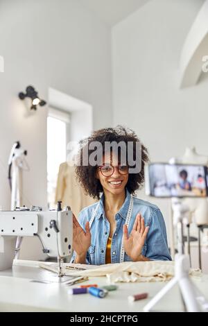 Positive African-American dressmaker shoots tutorial at workplac Stock ...