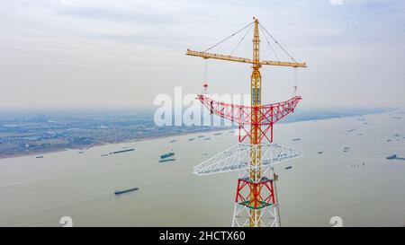 Workers labor at the world's tallest transmission towers that support the 2,656-meter-long power ...