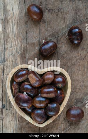 Heart shaped fresh chestnuts on brown wooden background Stock Photo - Alamy