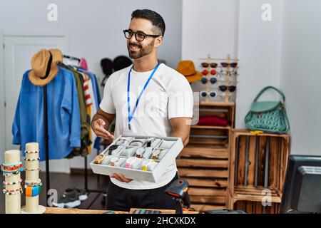 Young hispanic man shopkeeper showing screen smartphone working at ...