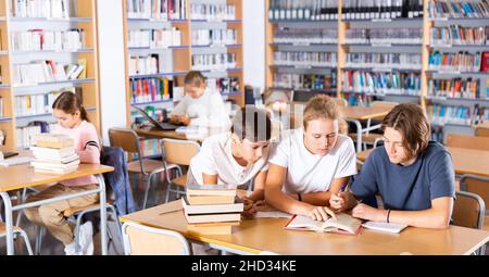 Three schoolchildren writes synopsis in an exercise book from the ...