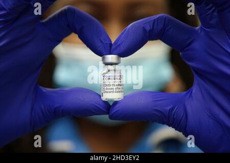 A health worker holds a Pfizer/BioNTech Covid-19 vaccine vial at a ...