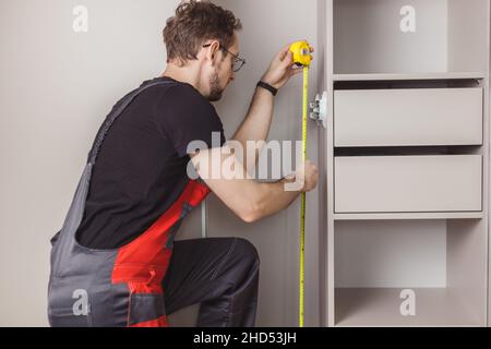 Master takes measurements during the installation of the wardrobe and ...