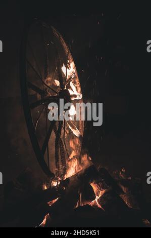 an old wheelchair burning in a fire with flames in the wheels in the ...