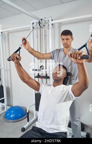 Young african physiotherapist man working at pain recovery clinic ...