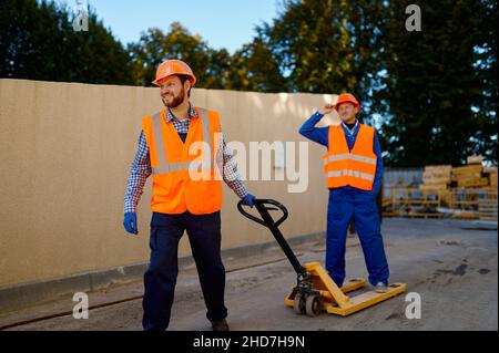 Builder worker using hand loader pallet truck Stock Photo - Alamy