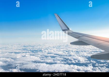 Travel concept. Wing of airplane flying above the clouds in trendy ...