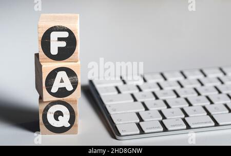FAQ on wooden blocks on office desk with computer keyboard, frequently ...