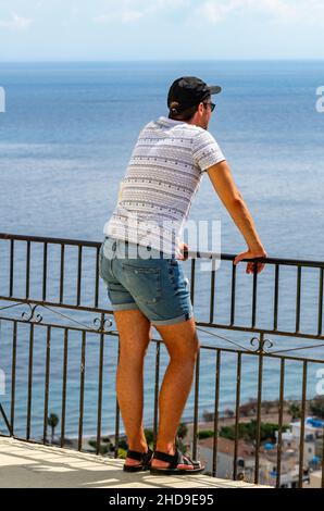 Man leaning on railings on sea front Stock Photo - Alamy