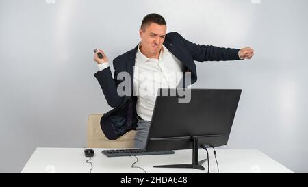 The man gets angry and smashes the monitor with a hammer. An office ...