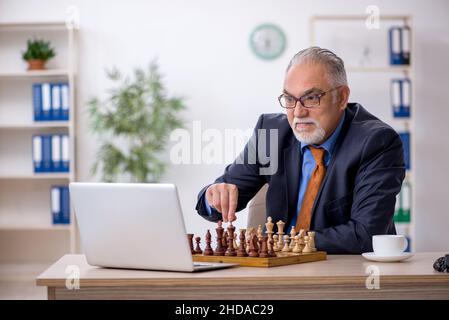 Old businessman playing chess in the office Stock Photo - Alamy