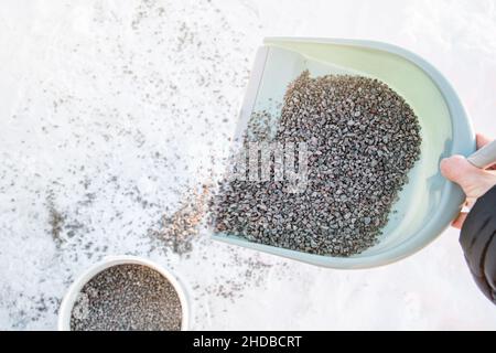 Gravel used on slippery streets roads. Person scattering gravel sand on ...