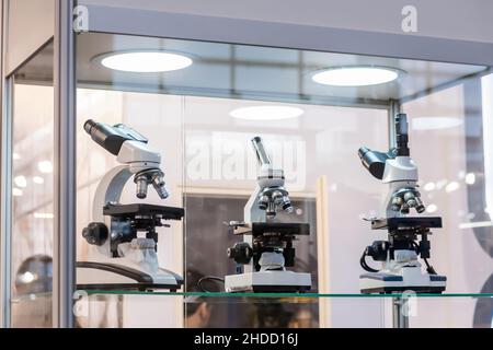 Three microscopes in glass showcase at science exhibition - laboratory ...