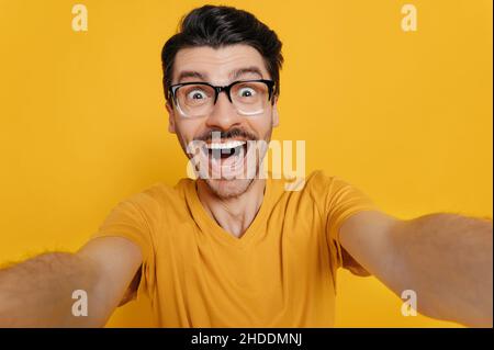 Photo of cheerful excited guy dressed pink t-shirt dark eyewear smiling ...