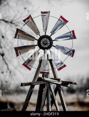 A vertical shot of an old windmill on a field in a rural area in sunny ...