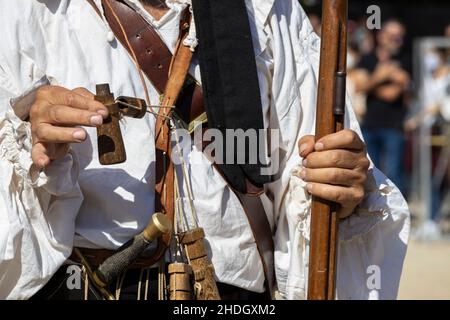 foreground hand showing the loading system of an arquebus. The arquebus ...