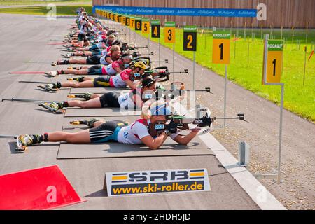 Group sportswoman biathlete aiming, rifle shooting and reloading rifle ...