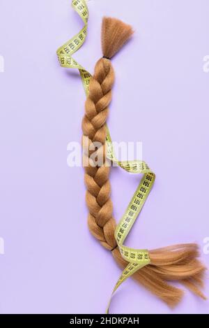 Braided red hair for donation with lilac ribbon and comb on grunge ...
