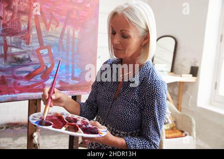 Female artist with color palettes drawing in workshop Stock Photo - Alamy