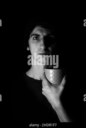 Grayscale shot of a young man holding a ginger car against a black ...