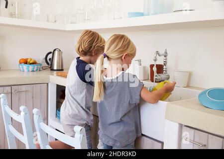 Child washing dishes. Kids wash plates and cups. Little girl helping in ...