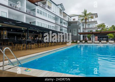 Vacationers in large swimming pool and others lounging on chairs near ...